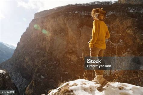 선글라스에서는 여자 사진 작가 큰 모피 모자와 노란색 니트 스웨터 그녀의 목에 Dslr 카메라와 함께 높은 바위 협곡에서의 배경 스탠드 가죽에 대한 스톡 사진 및 기타