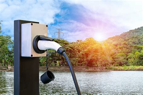 전기 자동차 충전 또는 자연 푸른 하늘 햇빛에 하이브리드 자동차에 대 한 Ev 스테이션 플러그 및 전원 케이블 공급 및 강 및 녹색 산 배경에서 고전압 전기 극 기둥에 대한