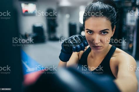 체육관 운동에 킥복싱 장갑과 가방을 펀칭 강한 갈색 매력적인 여성 트레이너의 전면 모습 스포츠 피트 니스 라이프 스타일 및 동기 부여 개념입니다 갈색 머리에 대한 스톡 사진