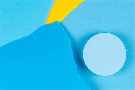 제품 디스플레이 노란색 및 파란색 찢어진 종이 조각을 위한 기하학적 원형 포디움에 대한 상단 보기 밝은 파란색 종이 배경에 노란색과 파란색 찢어진 종이 조각 강단에 대한