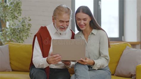 Old People And Digitalization Young Woman Showing Laptop To Senior Grandfather Teaching To Use