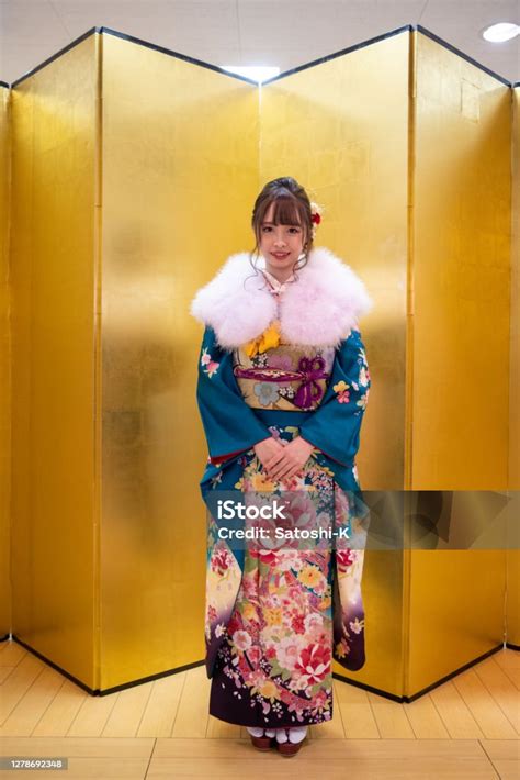 세이진시키 성년의식 용 황금 바이오부 접이식 스크린 앞에 모피 목을 훔친 후리소드 기모노를 입은 젊은 여성의 전체 길이 초상화