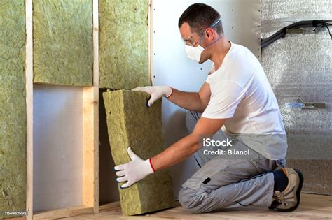 보호 고글및 호흡보호구에서 작업자가 차가운 장벽을 위한 미래의 집 벽을 위해 나무 프레임에 바위 울 절연을 절연합니다 편안한 따뜻한 집 경제 건설 및 리노베이션 개념