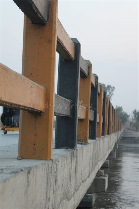 concrete bridge with orange and gray railings stretches across a river