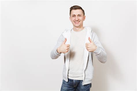 T셔츠 청바지와 가벼운 운동복 엄지손가락을 보여주는 젊은 잘생긴 웃는 남자 학생에 고립 된 흰색 배경에 기 뻐 합니다 감정 좋은 분위기의 개념입니다 광고에 대 한 공간을