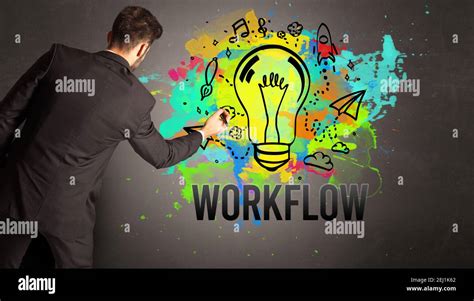Businessman Drawing Colorful Light Bulb With Workflow Inscription On Textured Concrete Wall New