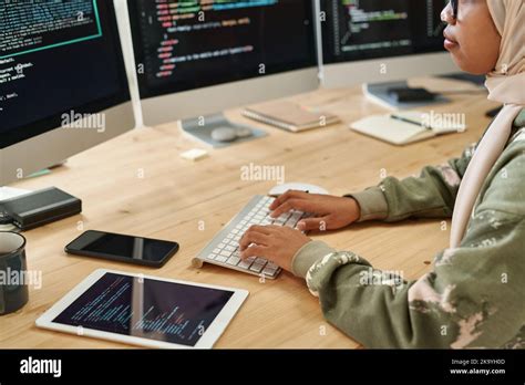 Young Muslim Intern In Hijab Typing On Keyboard While Decoding Data On Computer Screens By