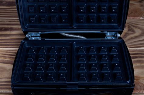 나무 테이블에 홈 키친에서 벨기에 또는 비엔나 와플을 요리하기위한 와플 아이언을 엽니 다 기계류에 대한 스톡 사진 및 기타