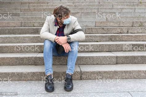 보호 마스크를 쓴 실업사업가는 세계 경제 위기로 인해 직장을 잃었고 야외에서혼자 계단에 앉아 있었다 실업 개념 사람들에 대한