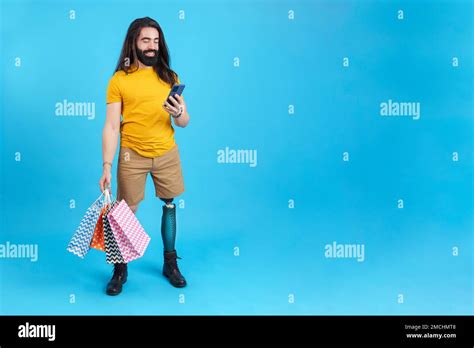 Man With Prosthetic Leg Using The Mobile Holing Shopping Bags Stock