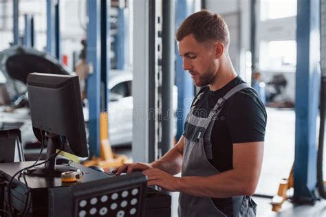 Diagnostic Pc Man At The Workshop In Uniform Use Computer For His Job For Fixing Broken Car