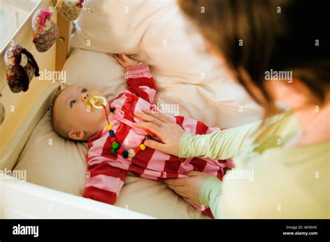 Mother Fondling Her Baby In Bed With Comforter Stock Photo Alamy