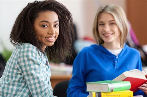 Dos Mujeres Jóvenes Con Libros En Biblioteca Foto Premium