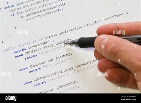 a programmer man pointing with his pen at java computer code