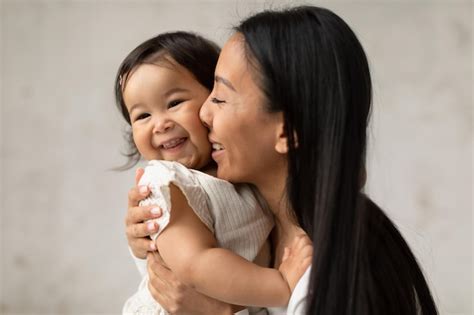 Feliz Madre Japonesa Frotando La Nariz En La Mejilla De Las Hijas Del Beb En El Interior Foto