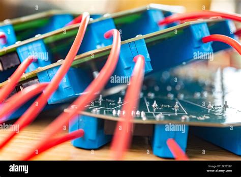 Close Up Of A Large Green Microcircuit With Red HI Voltage Wires And Blue Relays Connected To It