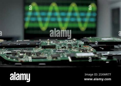 A Circuit Board Is Placed In The Foreground While An Oscilloscope In The Background Displays