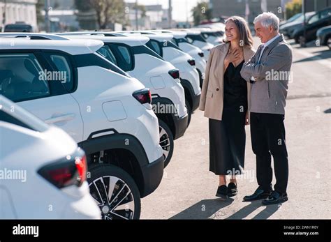 Mature Caucasian Couple Walks Past Cars Outdoors Choosing A New One