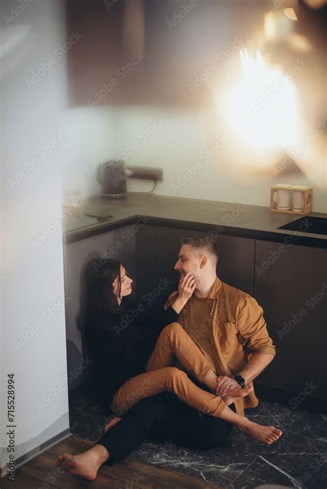 Сouple Is Sitting On The Floor In The Kitchen The Girl Smiling Threw