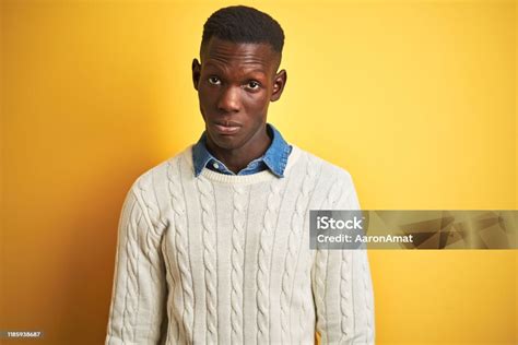 데님 셔츠와 흰색 스웨터를 입은 아프리카 계 미국인 남자가 고립 된 노란색 배경 에 회의적이고 긴장하고 문제로 인해 화가 났습니다 부정적인 사람 감정에 대한 스톡 사진 및