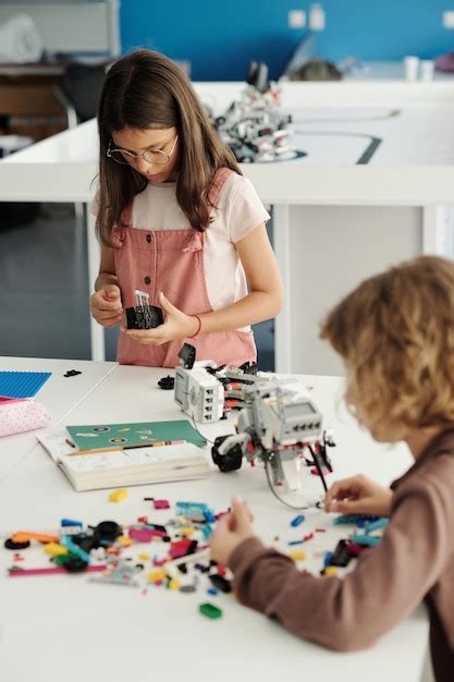 Dos Escolares De Primaria Parados Junto A La Mesa Con Detalles Del Robot En La Lección Foto