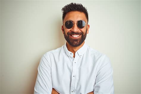 고립된 흰색 배경 위에 셔츠와 선글라스를 착용한 잘생긴 인도 의 Buinessman은 카메라를 보고 교차 팔로 미소 짓는 행복한 얼굴입니다 긍정적 인 사람 선글라스에 대한