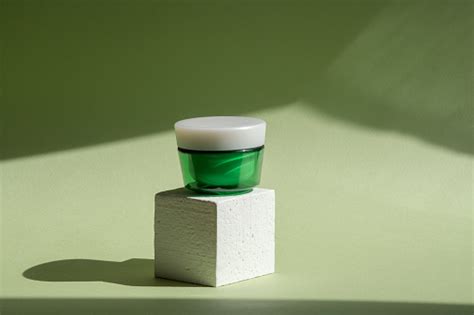 녹색 크림 항아리 흰색 뚜껑 햇빛에 사각형 스탠드에 오브젝트는 밝은 녹색 배경의 표면에 그림자를 투사합니다 미용 바디 케어용 제품을 시연하는 컨셉 3d 시상대 0명에 대한