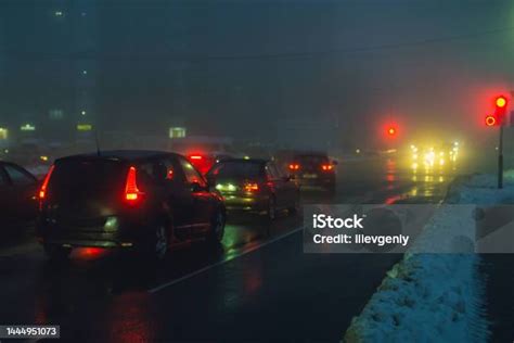 안개가 낀 날씨 밤 안개 도로에서 시야가 좋지 않습니다 자동차의 움직임 교통 체증 젖은 미끄러운 아스팔트 자동차 헤드 라이트 빛의 광선 도로에 눈과 얼음 도시 거리 도시에