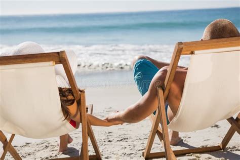 Cute Couple Holding Hands While Lying On Their Deck Chairs Stock Image