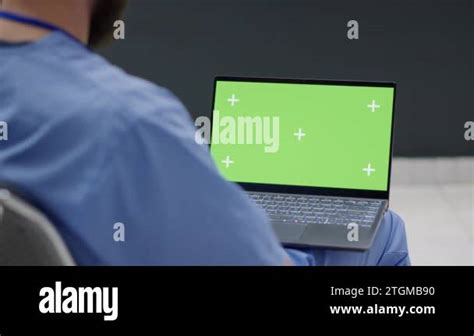 Male Nurse Holding Laptop With Greenscreen Template In Waiting Room