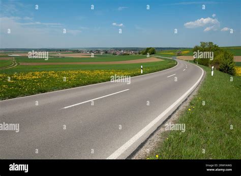 Rural Two Lane Roadway Passing Through Lush Farmlands With White