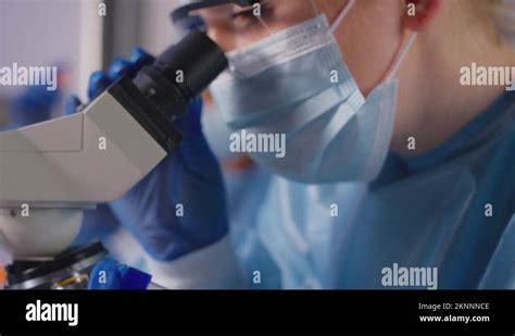 Female Lab Worker Wearing PPE Analysing Samples With Microscope Holding Test Stock Video Footage
