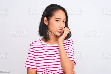 줄무늬 티셔츠를 입은 젊은 중국 여성은 손톱을 물고 손톱을 물고 손에 스트레스와 긴장 찾고 고립 된 흰색 배경 위에 서있다 불안 문제 수줍어하는에 대한 스톡 사진 및 기타