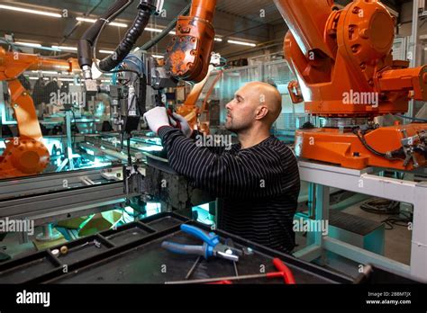 Engineer Doing Maintenance On A Automatic Robot Arms In Automotive