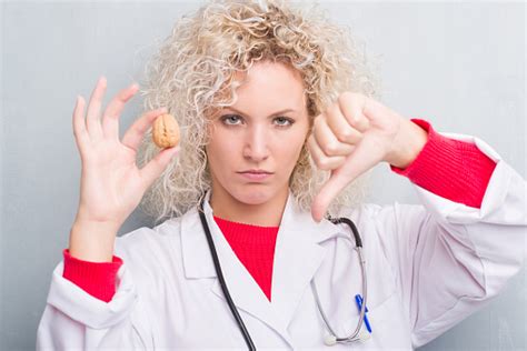 그런 지 위에 젊은 금발 영양사 의사 여자 회색 벽 잡고 성 난 얼굴 아래로 엄지 싫어 보여주는 음수 부호 거부 개념 호두 개념에 대한 스톡 사진 및 기타 이미지 Istock