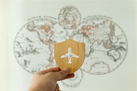 흐릿한 세계지도 배경으로 여행 보험을 나타내는 비행기 기호가 있는 보험 기호를 들고 있는 보험 대리인 글로벌 여행자 보험의 개념