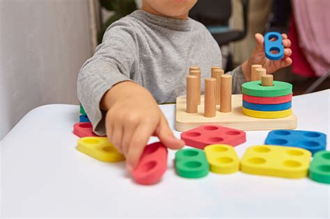 아이는 선별기를 수집합니다 아이들을위한 교육 논리 장난감 아이들의 손을 클로즈업 몬테소리 어린이 발달 게임 흰색 배경에 여러 가지 빛깔의 논리 선별기 교육에 대한 스톡 사진