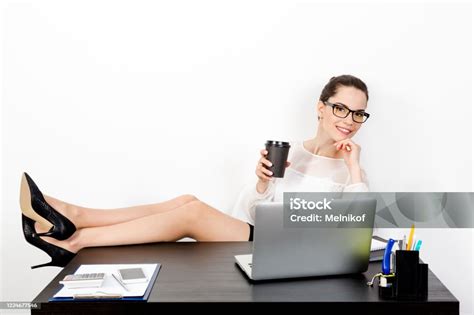 한 젊은 잘생긴 사업가가 편안한 자세로 직장에 앉아 다리를 탁자 위에 올려놓고 신발과 커피 한 잔을 들고 있습니다 문제 해결의 용이성의 개념 개념에 대한 스톡 사진 및 기타