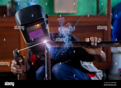 A Welder Wearing A Protective Helmet Is Welding A Metal Frame With