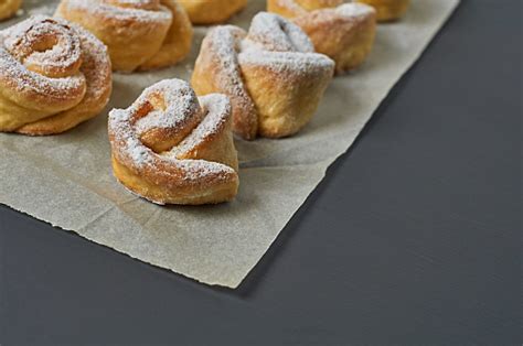 종이에 가루 설탕을 넣은 장미 형태의 많은 수제 구운 빵은 어두운 콘크리트 책상 위에 놓여 있습니다 제과 작업장 텍스트를 위한 공간 가루 설탕에 대한 스톡 사진 및 기타