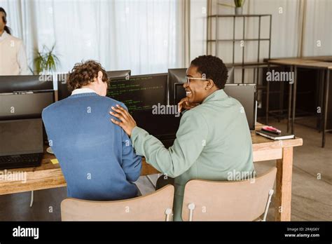 rear view of smiling female programmer sitting with male colleague at
