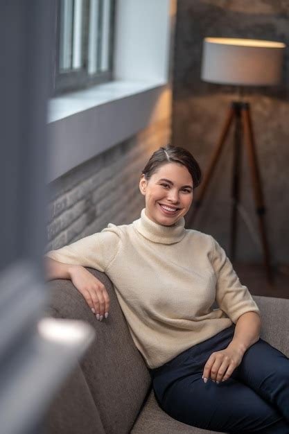 Free Photo Smiling Pleased Woman Seated On The Sofa Looking Ahead