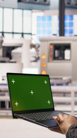 vertical factory engineer typing on green screen laptop monitoring