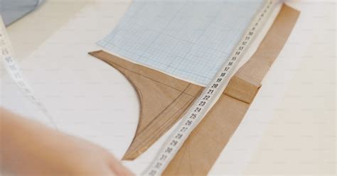 Atelier의 테이블에 바느질 패턴을 측정하는 테이프를 가진 여성 재단사 직장에서 종이 패턴으로 작업하는 개 옷 디자이너 사진 Unsplash의 손 이미지