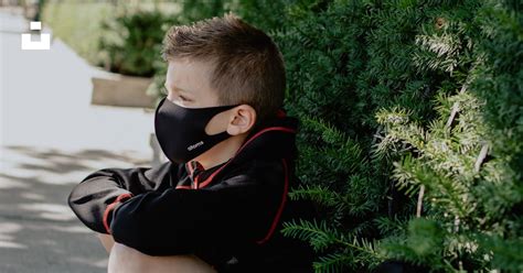 낮에는 회색 콘크리트 바닥에 앉아 있는 검은색과 빨간색 까마귀를 입은 소년 사진 Unsplash의 무료 원자 이미지