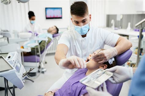 치과 진료소에서 어린 소녀의 치아를 검사하는 젊은 치과 의사 25 29세에 대한 스톡 사진 및 기타 이미지 25 29세 30 34세 4 명 Istock