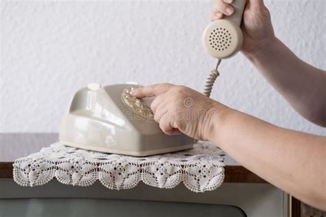 Mature Female Hand Removing Handset Rotating Dialer On Old White Rotary Telephone With Disc