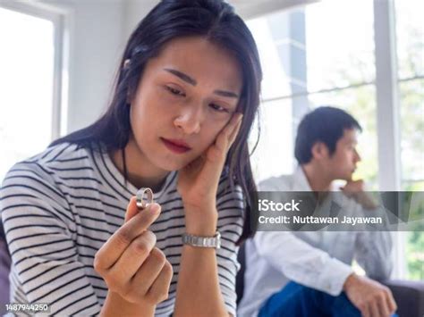 아시아 여성은 결혼 반지를 끼고 앉아 남편과 말다툼을 한 후 심각하게 슬프고 슬프다고 생각했다 연인의 문제는 분리되어야합니다 가족 문제 이혼 세탁 손실 2명에 대한 스톡