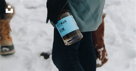 손에 음료수를 들고 눈 속에 서 있는 남자 사진 Unsplash의 무료 코트 이미지