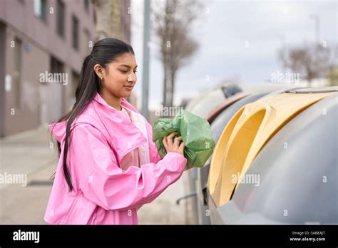 Young Woman Throwing Garbage In Recycling Bin Promoting Environmental